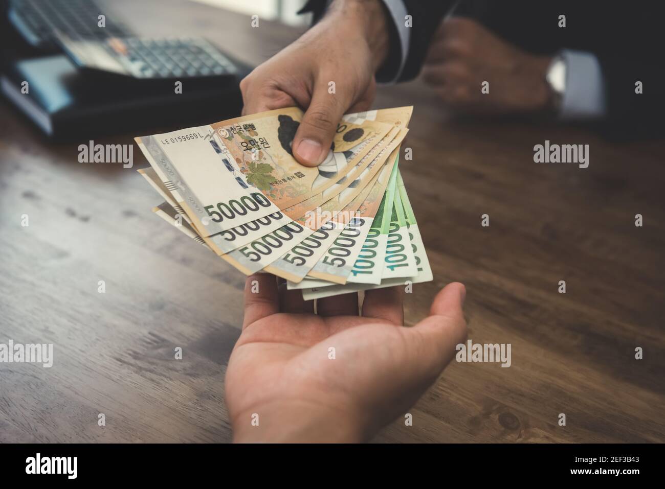 Businessman giving money, Korean won banknotes, to his partner ...