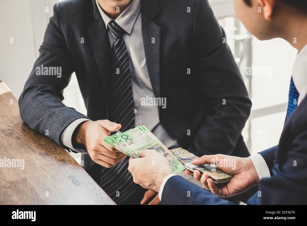 Businessman giving money, Australian dollar bills, to his partner ...