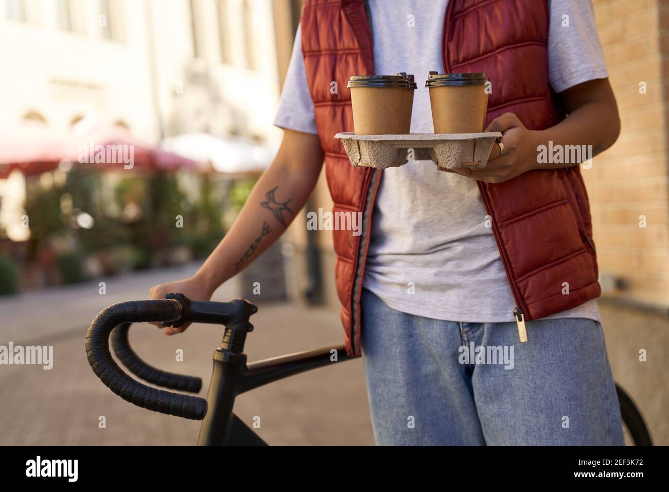 Cropped shot of a male courier delivering four coffee cups to customer ...