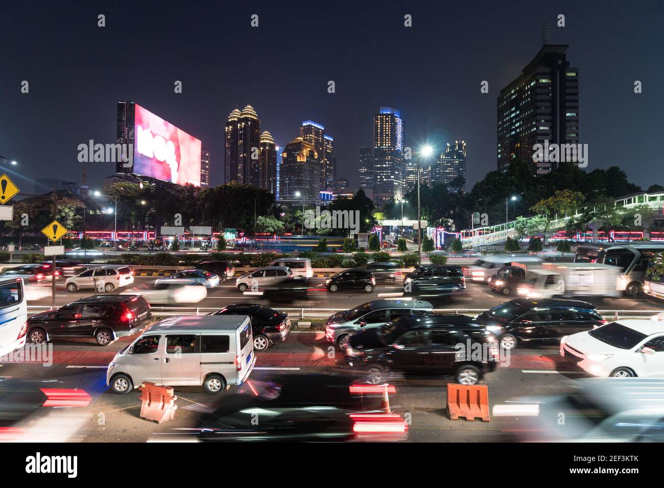 Traffic captured with blurred motion in the modern Jakarta downtown district along a crowded ...