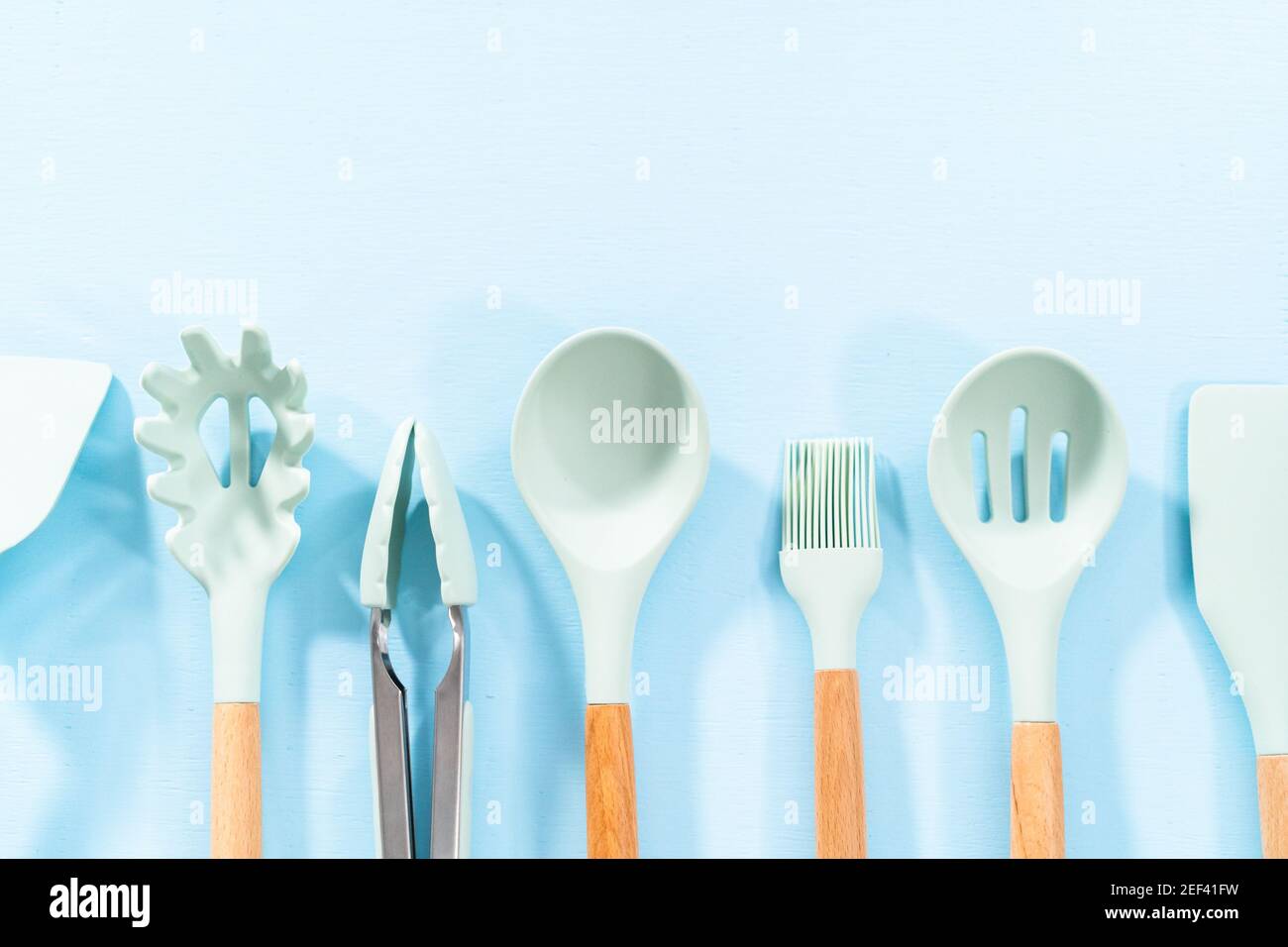 New blue silicone kitchen utensils with wooden handles on a blue ...