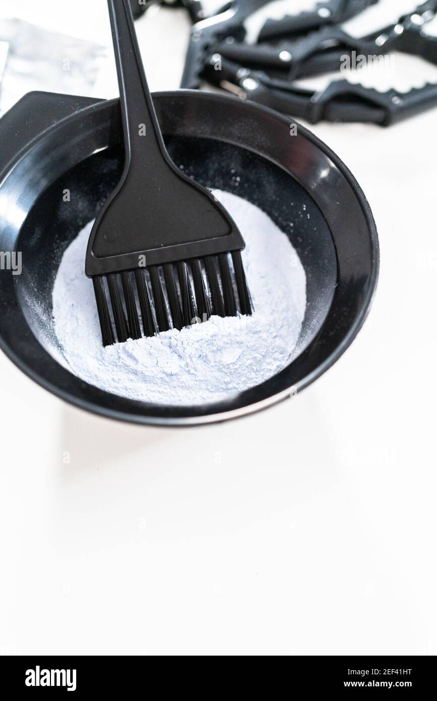 Hair color dye powder in a black plastic mixing bowl on a white ...
