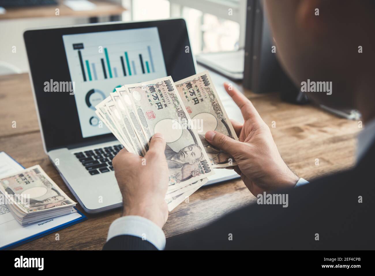 Businessman counting money, Japanese yen banknotes, at working desk ...