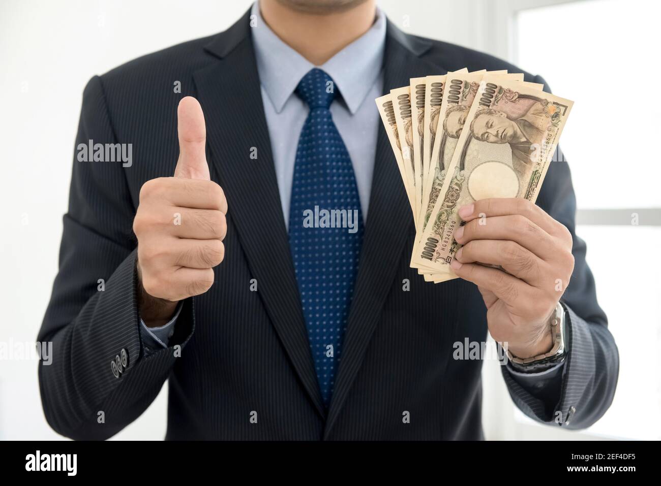 Businessman showing money, Japanese yen banknotes, and giving thumbs up ...