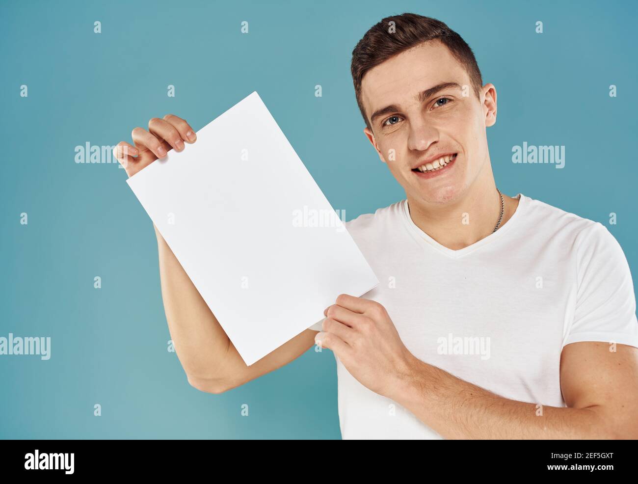 Happy guy shows a flyer in his hand on a blue background advertising ...