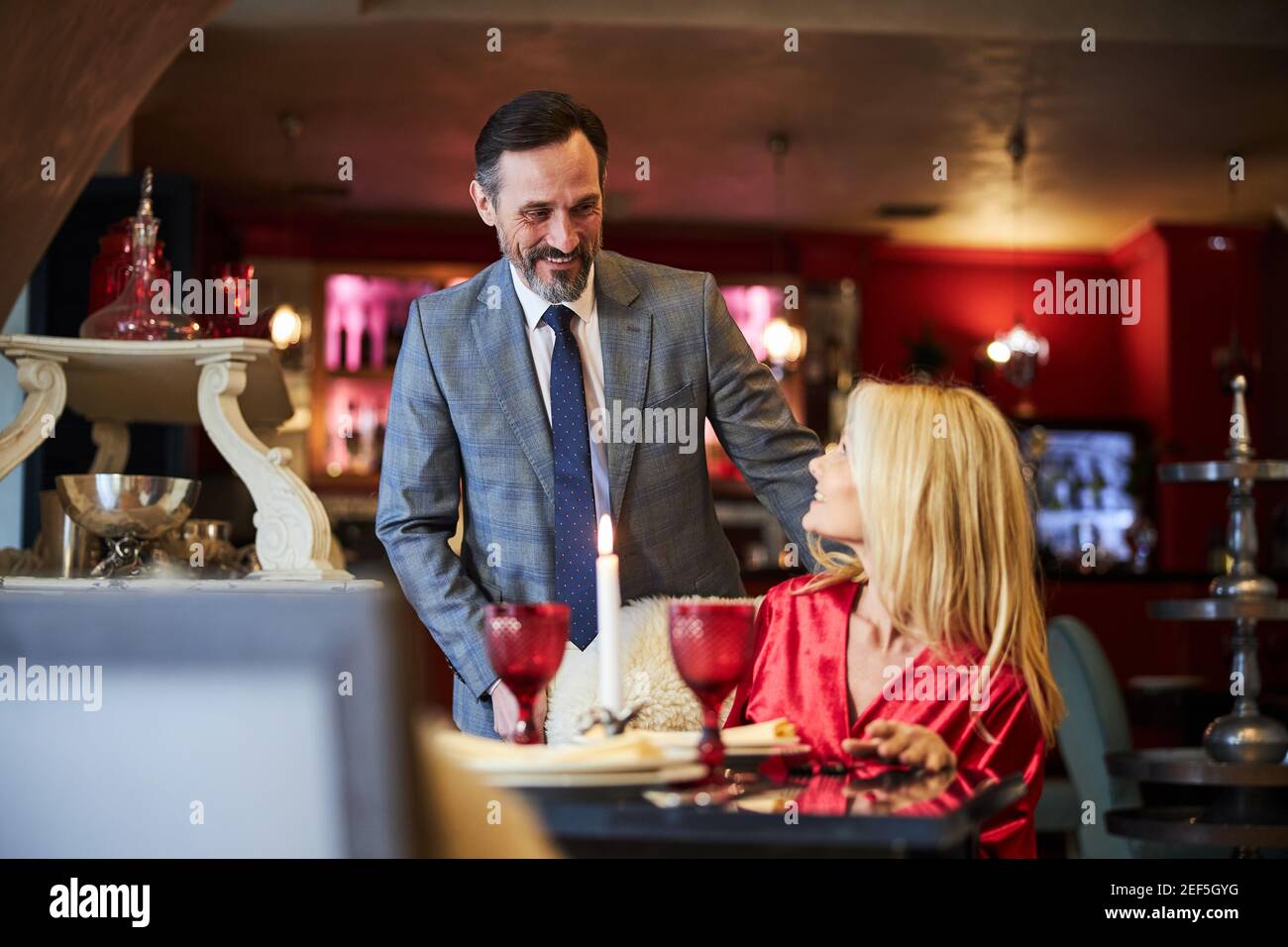Caring man assisting his lady with a restaurant seat Stock Photo - Alamy