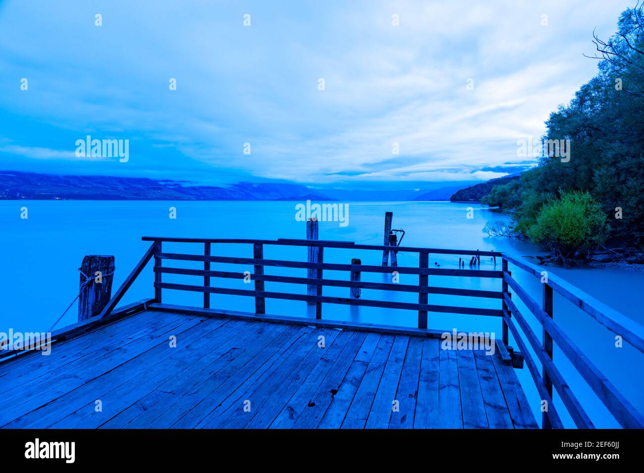 Old jetty with post and rail barrier in blue tones with long exposure ...