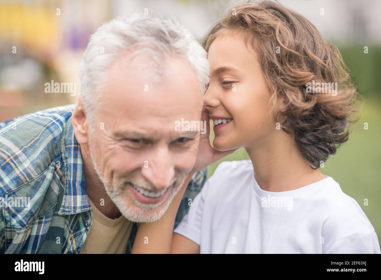 Cute dark-haired boy sharing secrets with his dad Stock Photo - Alamy