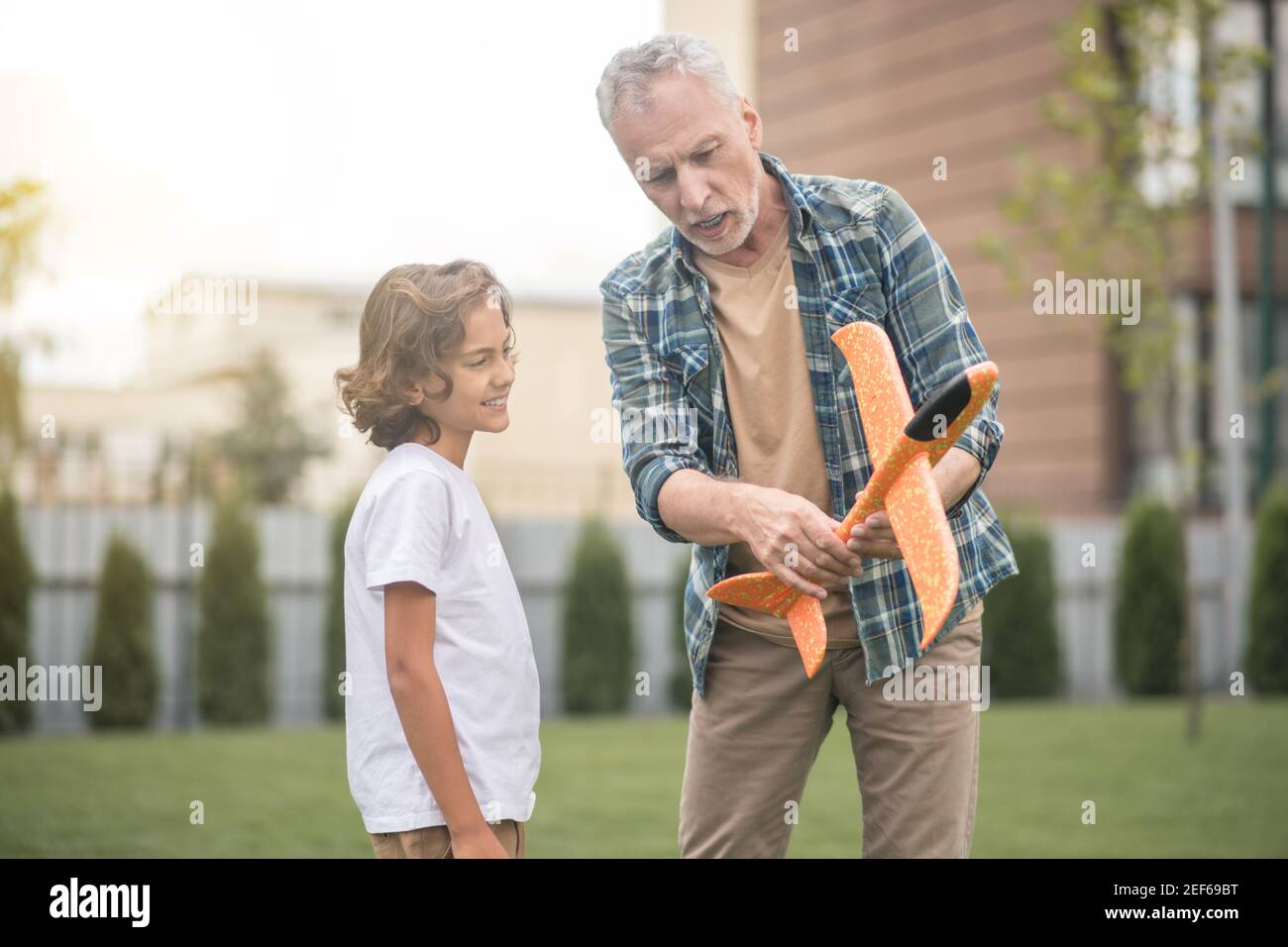 Gray-haired dad showing to his son how to use the toy plane Stock Photo ...