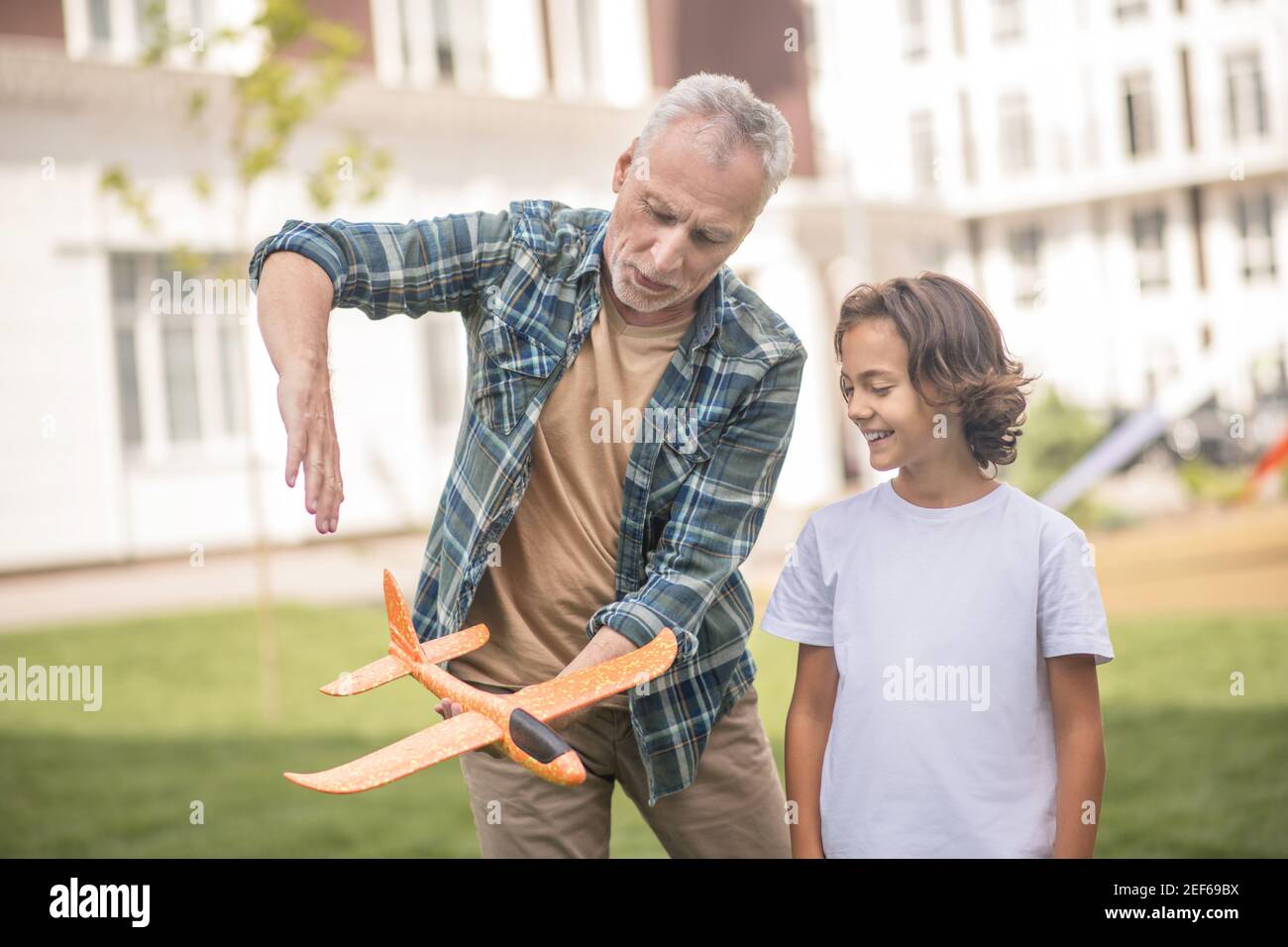 Gray-haired dad showing to his son how to use the toy plane Stock Photo ...
