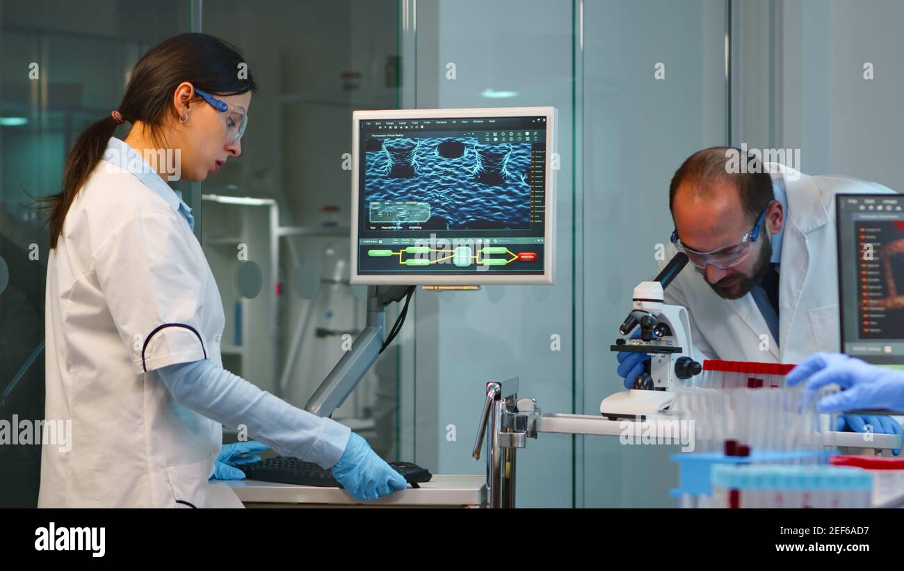 Scientist team checking virus development using microscope and nurse ...