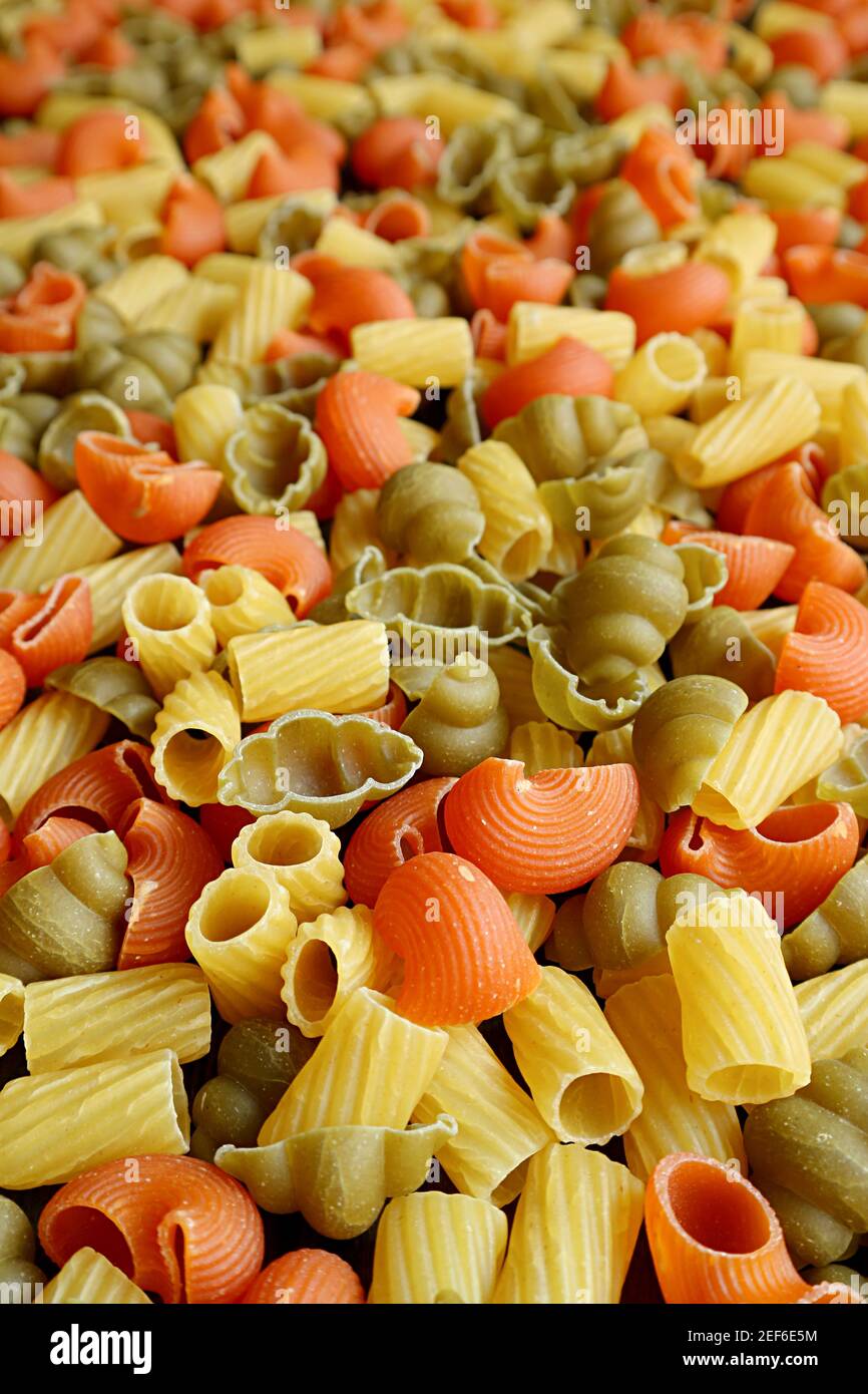 Vertical image of heap of three-color uncooked vegeroni pasta with ...