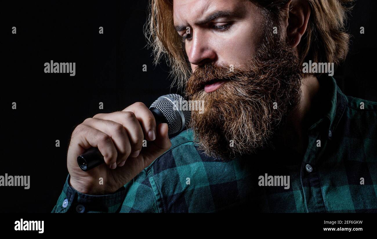Male attends karaoke. Man with a beard holding a microphone and singing ...