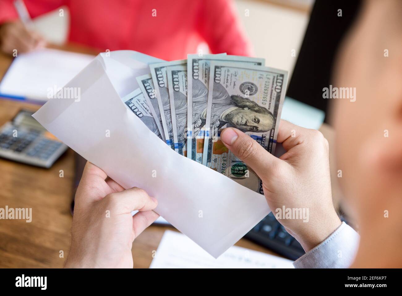 Businessman checking money inside the envelope at his working desk ...