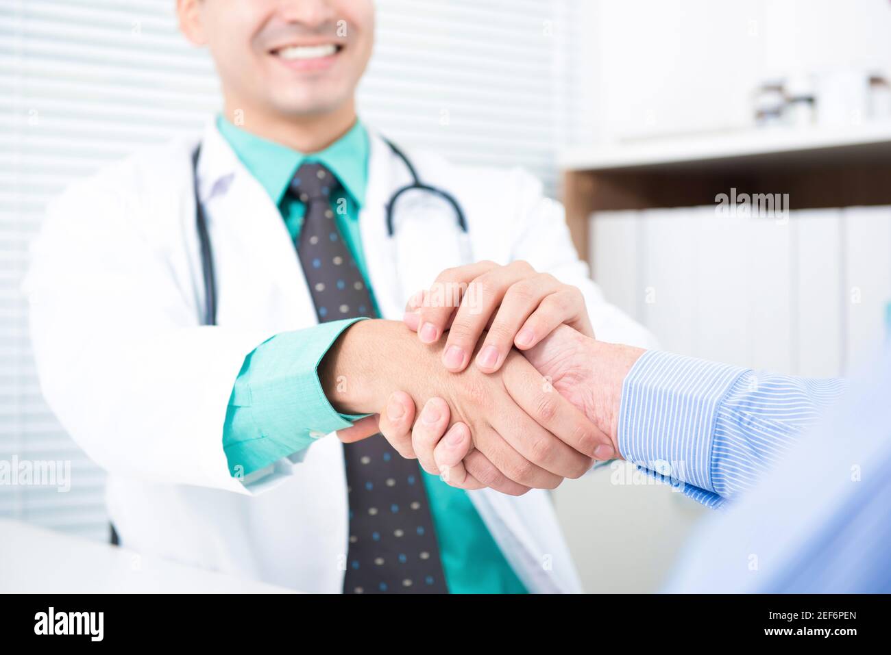 Doctor holding senior male patient hand with care Stock Photo - Alamy