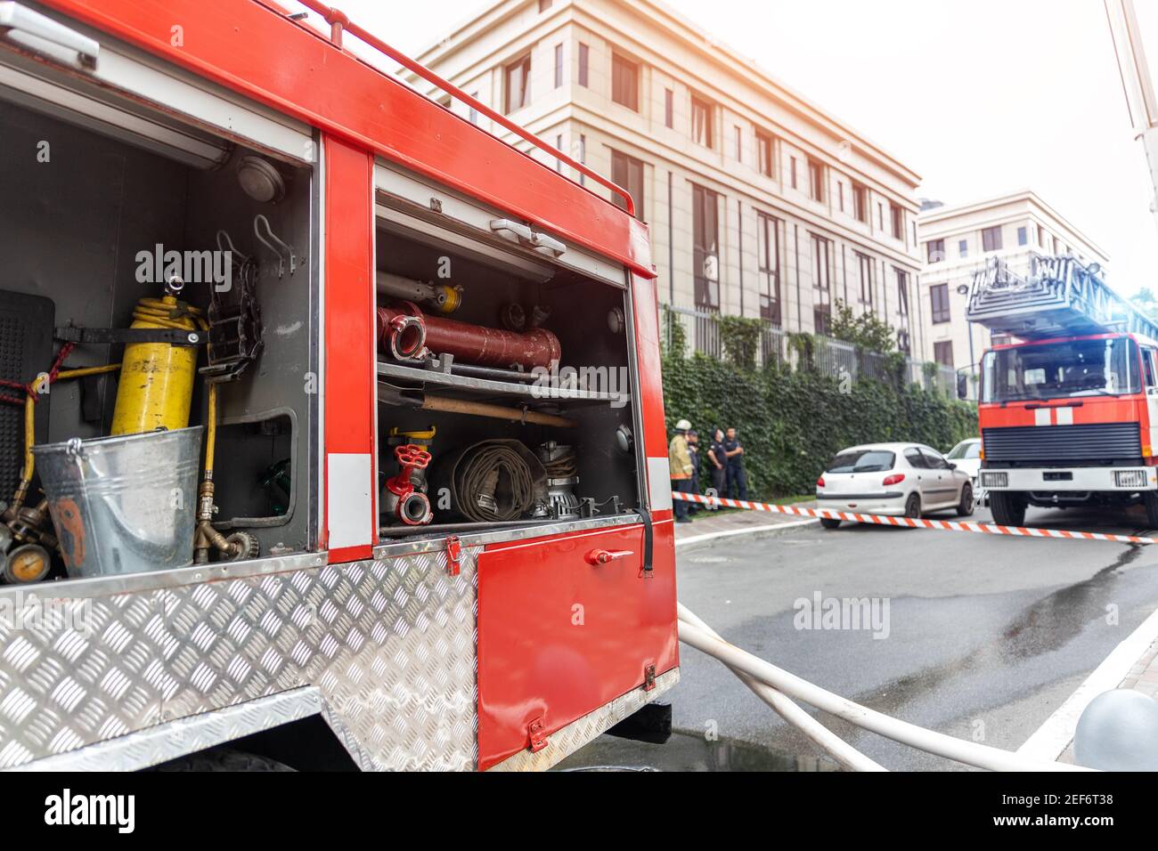 Firemen wearing uniform standing behind fire tape and many fire engine ...