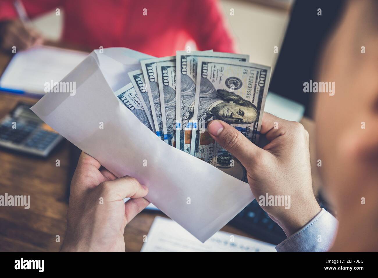 Businessman checking money inside the envelope at his working desk ...