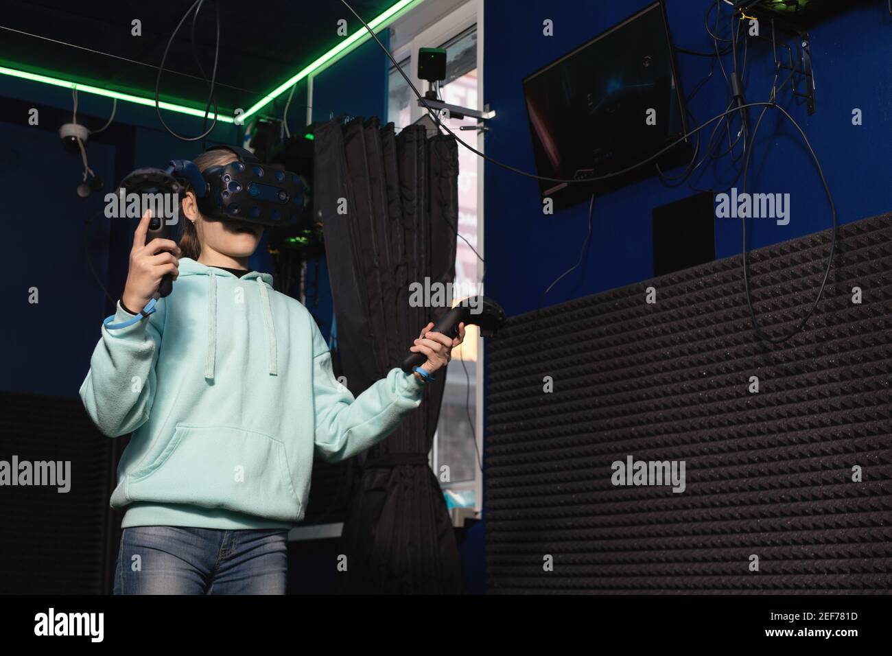Young teen girl is playing in virtual reality game club using joystick ...