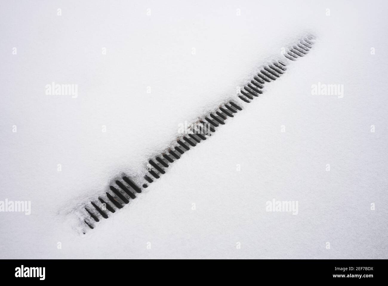 Frozen and snow-covered steel driveway drain grate after winter storm ...