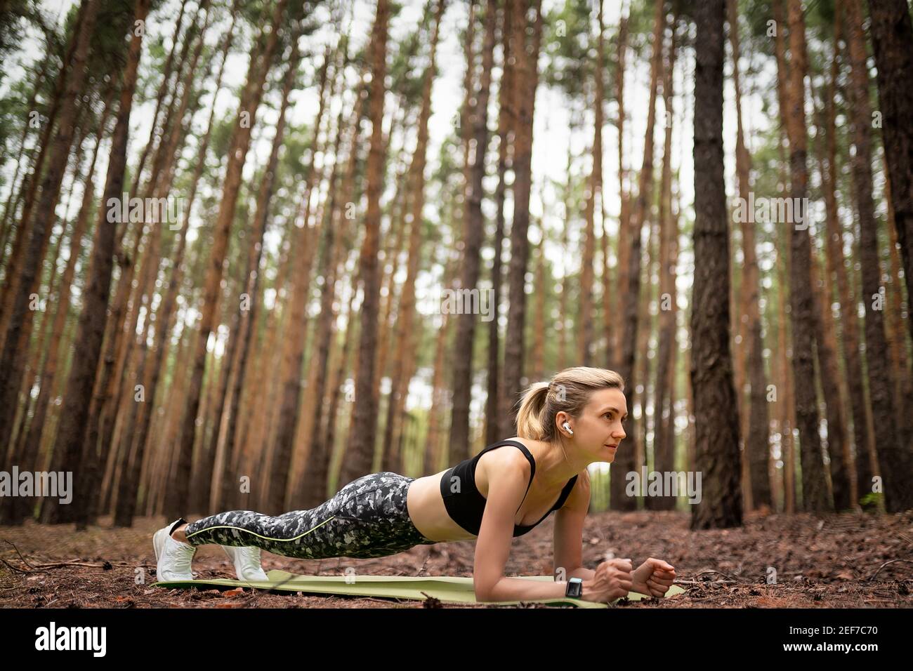 Woman doing forearm plank pose outdoors in forest on fresh air Stock ...