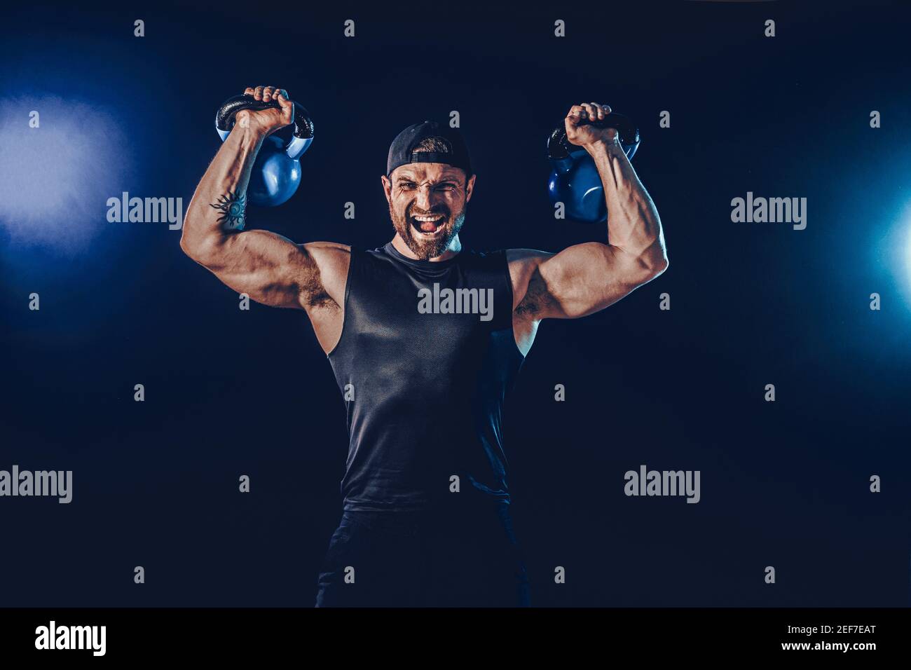 Aggressive bearded muscular bodybuilder doing Exercise for the shoulder ...