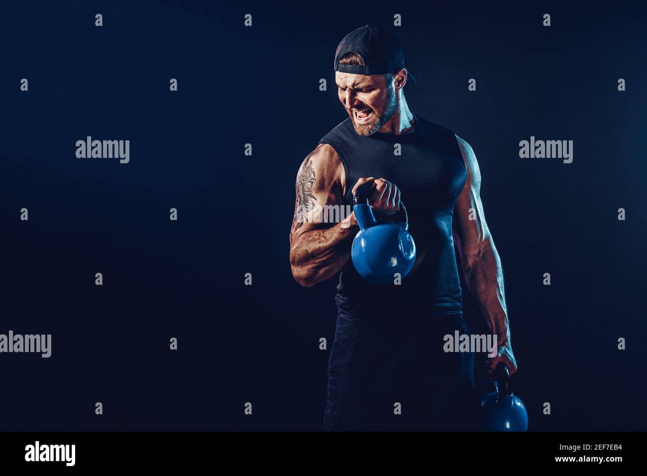 Aggressive bearded muscular bodybuilder doing Exercise for the shoulder ...