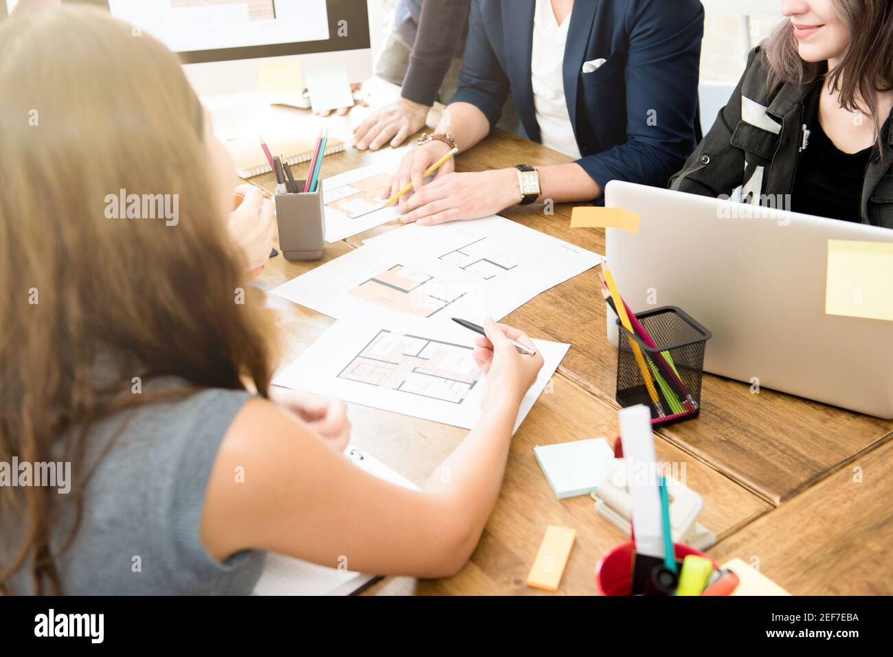 Group of architects (or interior designers) discussing floor plans in ...