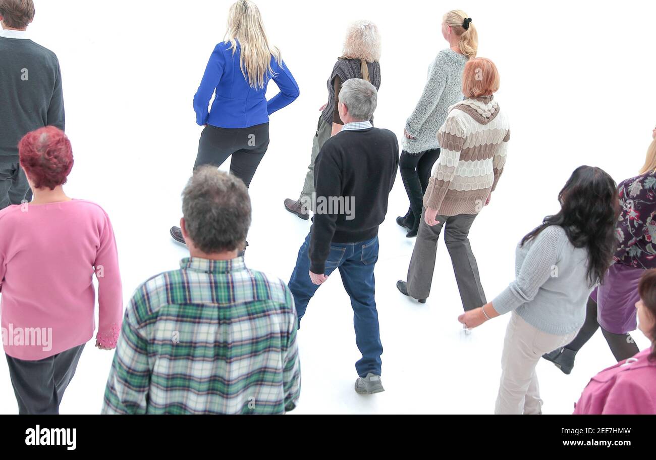 rear view. a group of different people walking in the same direction ...