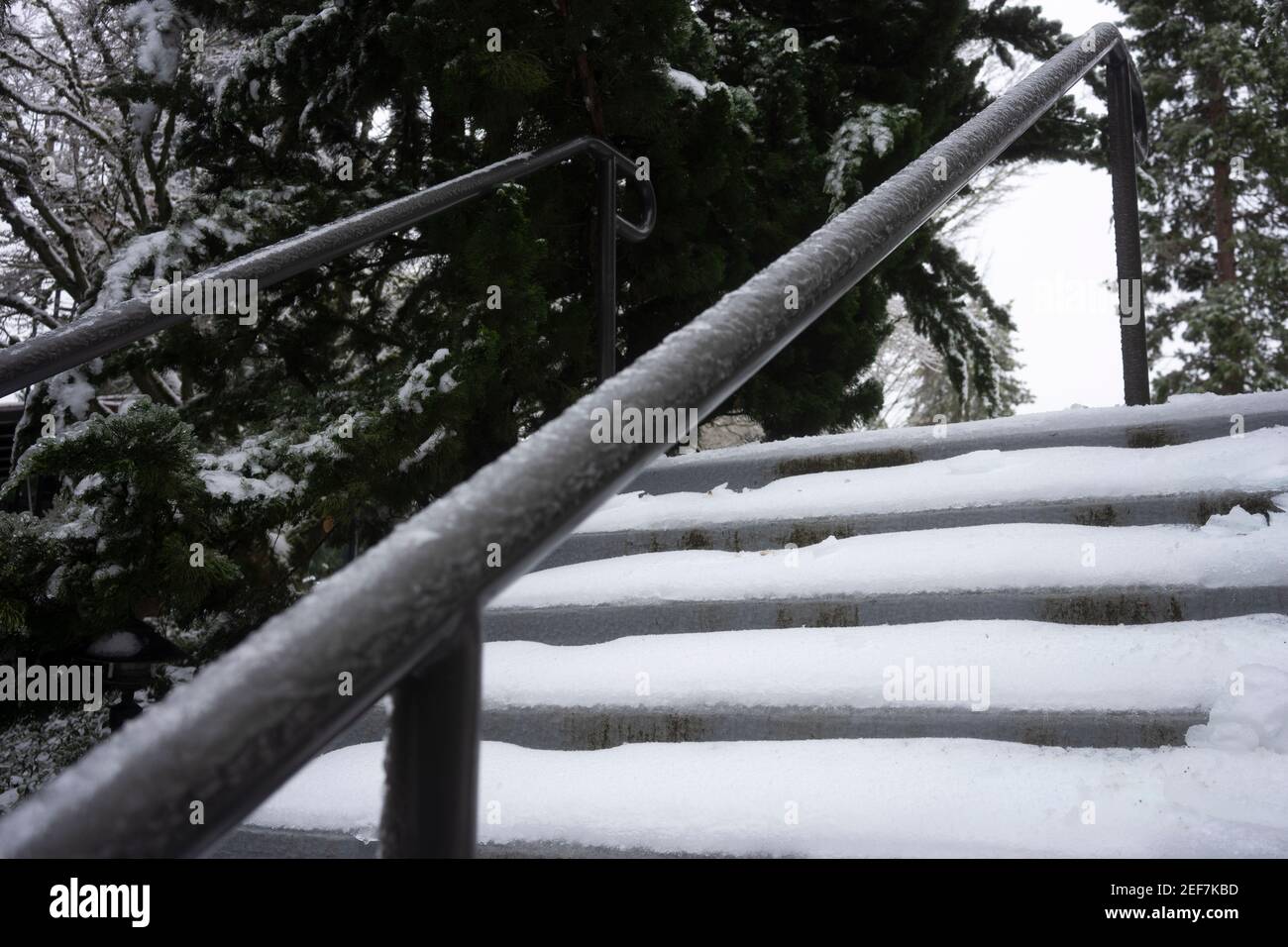 Snow-covered outdoor stairs and frozen railing after snow and freezing ...
