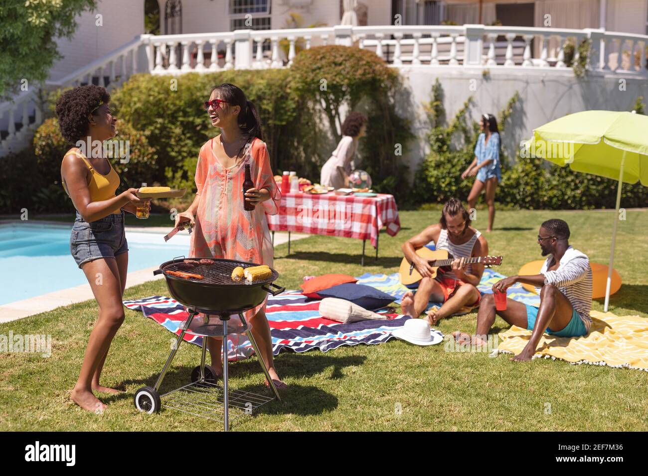 Diverse group of friends having barbecue and talking at a pool party ...