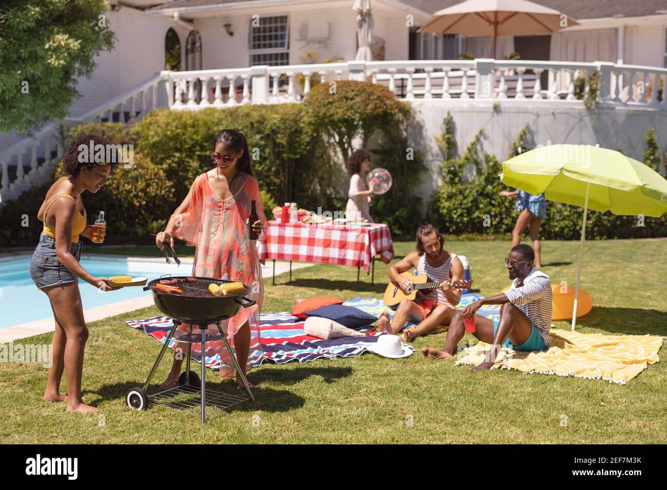Diverse group of friends having barbecue and talking at a pool party. Hanging out and relaxing ...
