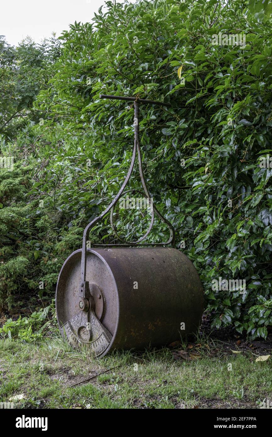 Vertical shot of an old and rustic cricket pitch roller with green ...