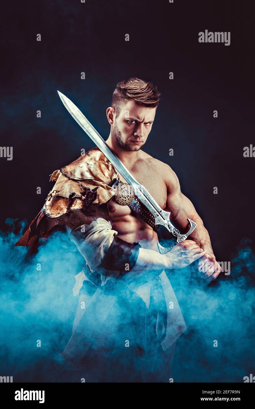 Portrait of angry gladiator with sword looking up against of black ...
