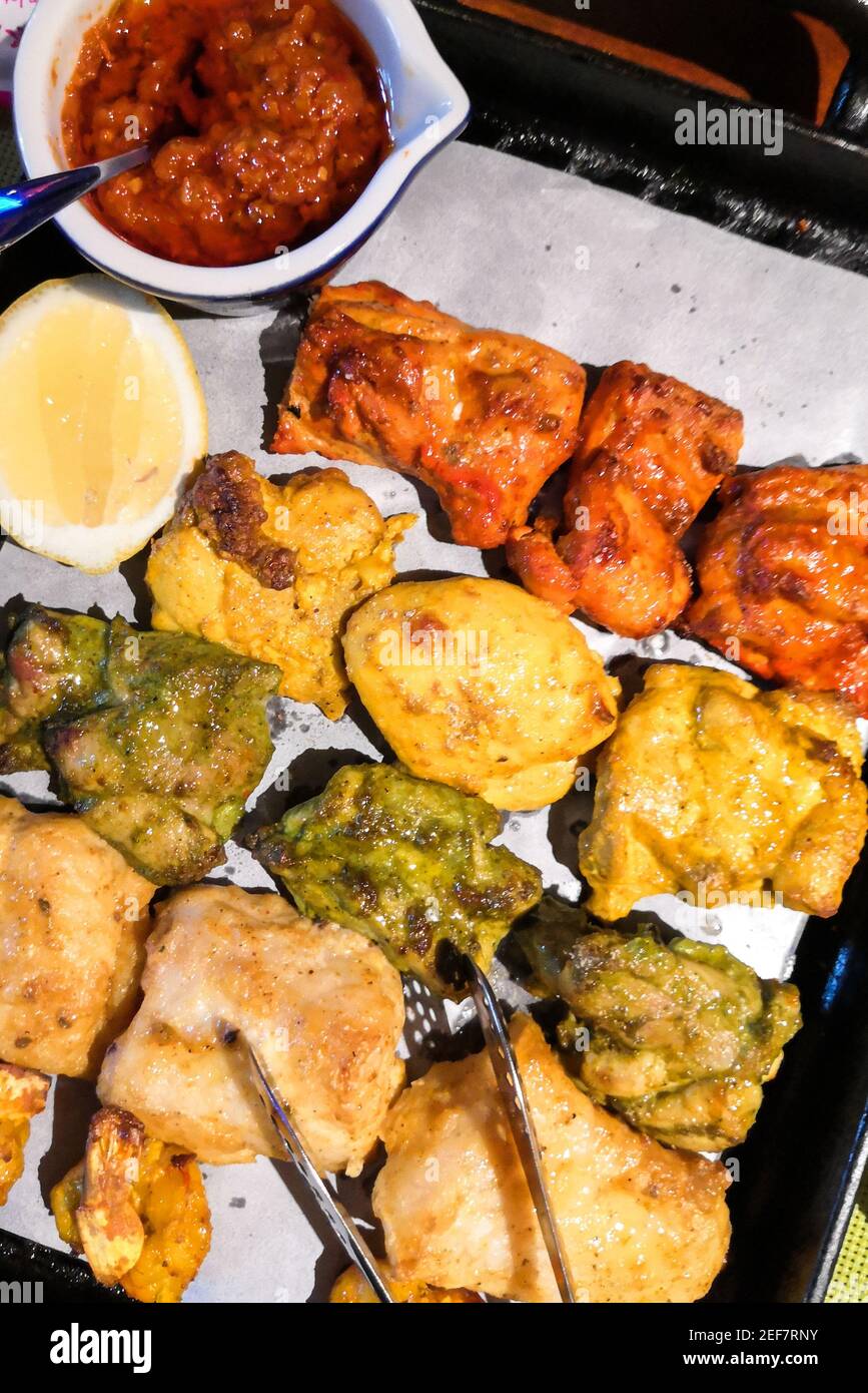 Vertical shot of Indian fried chicken and fish with sliced lemon on a ...