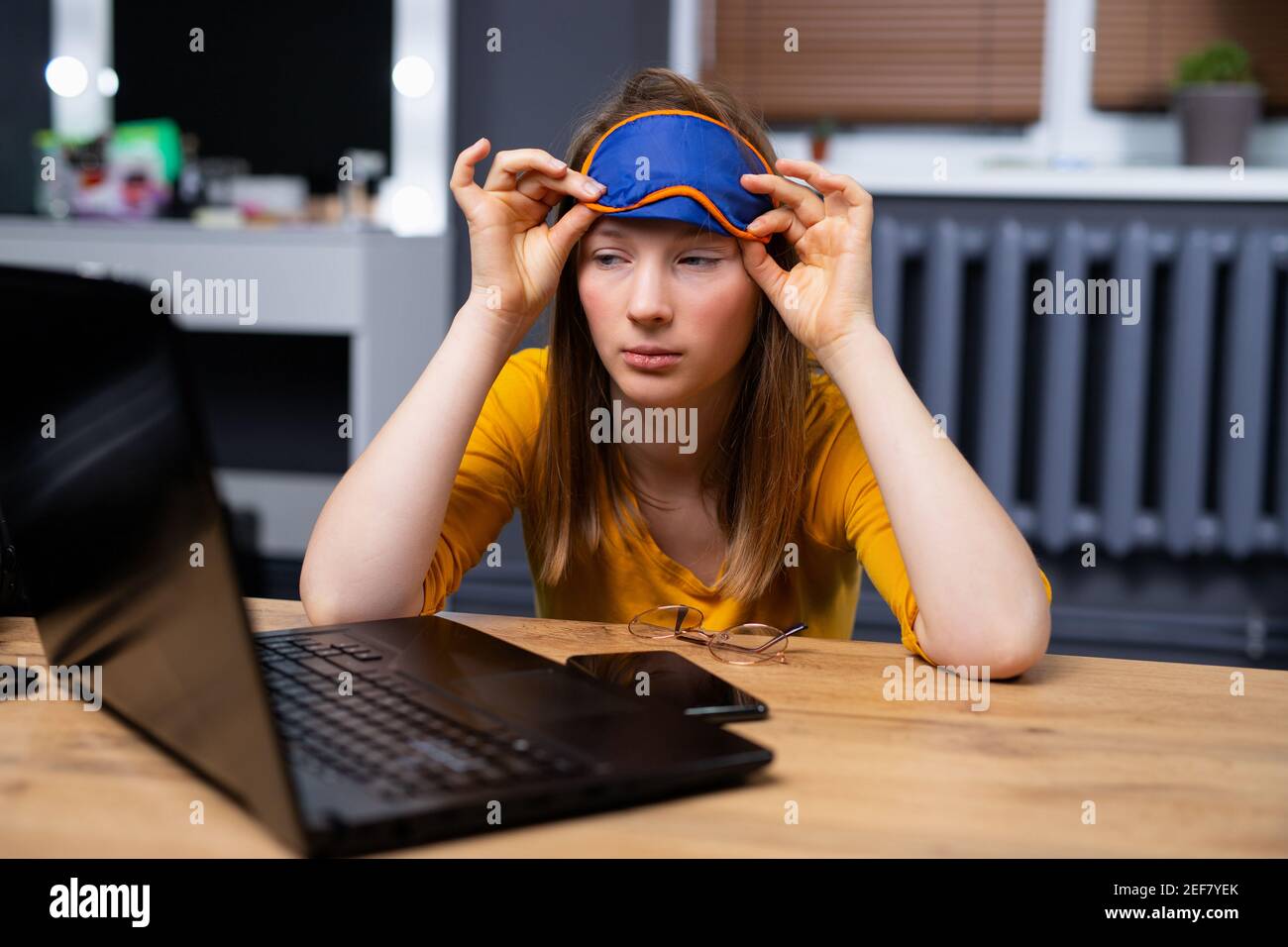 Bored sleepy young woman sit at home office table look in distance ...
