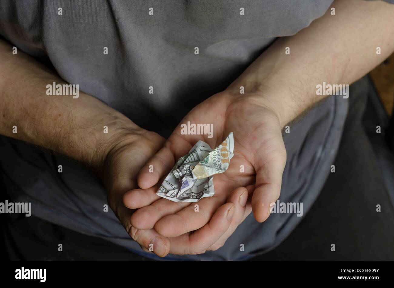 Crumpled money lies in open palms. An adult man is holding a wrinkled ...