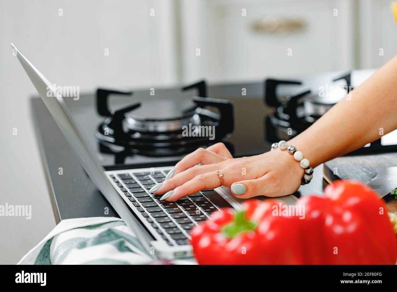Female using laptop while cooking in kitchen close up Stock Photo - Alamy