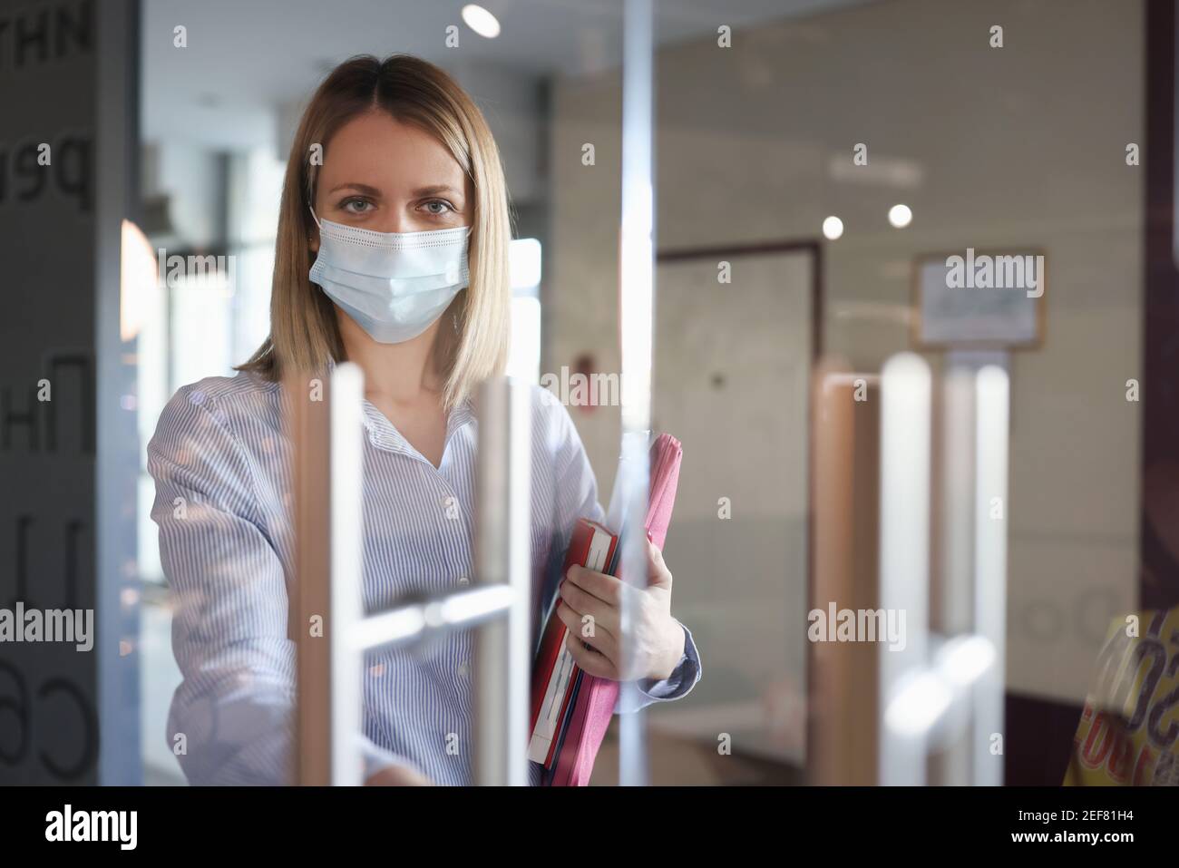 Woman in medical protective mask opens door Stock Photo - Alamy