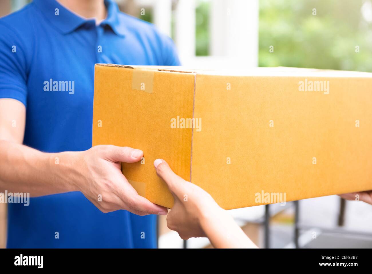 Delivery man in blue uniform handing parcel boxes to recipient ...