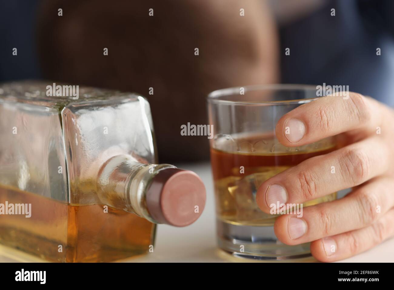 In man's hand glass with alcohol next to bottle Stock Photo - Alamy