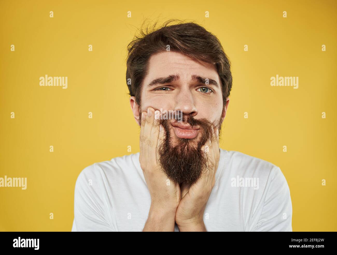 Frightened sad man touching face with hands on yellow background ...