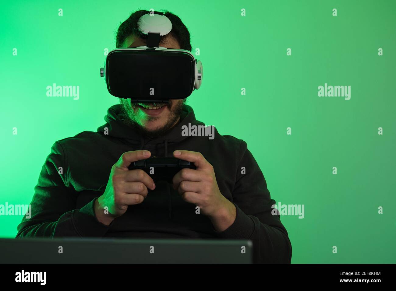 Gamer wearing virtual reality goggles, smiling and playing video games ...