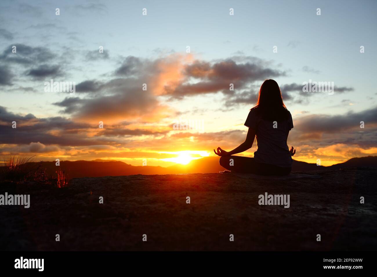 Back view portrait of a woman silhouette doing yoga at sunset in the ...