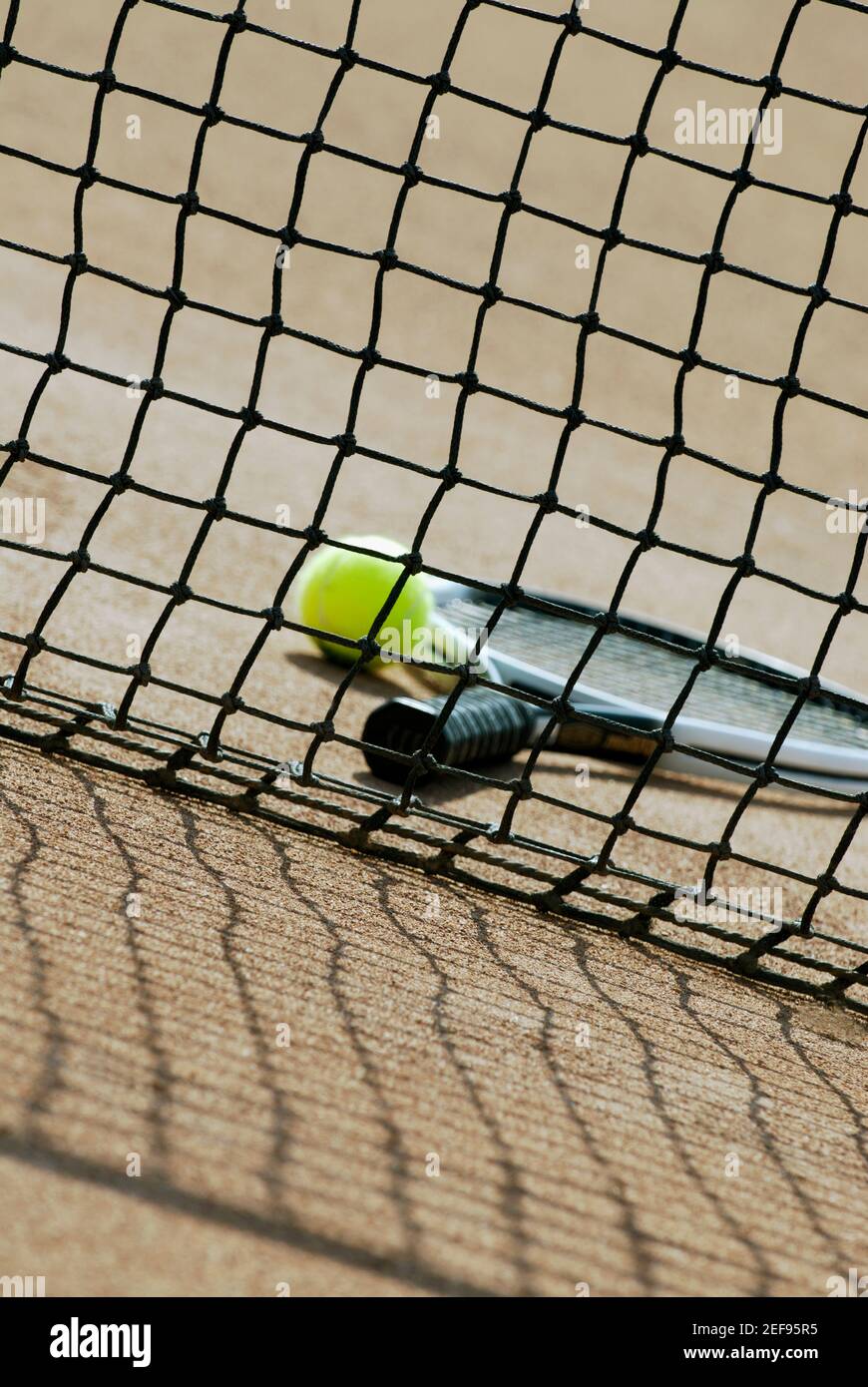 Tennis ball and a tennis racket behind a tennis net Stock Photo - Alamy