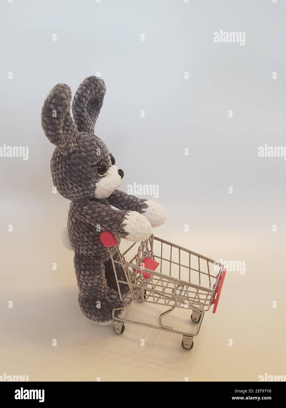 Close up of crocheted plush bunny with empty shopping trolley toy on ...