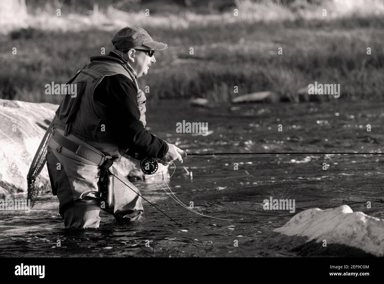 Senior man standing by river holding fishing rod hi-res stock ...