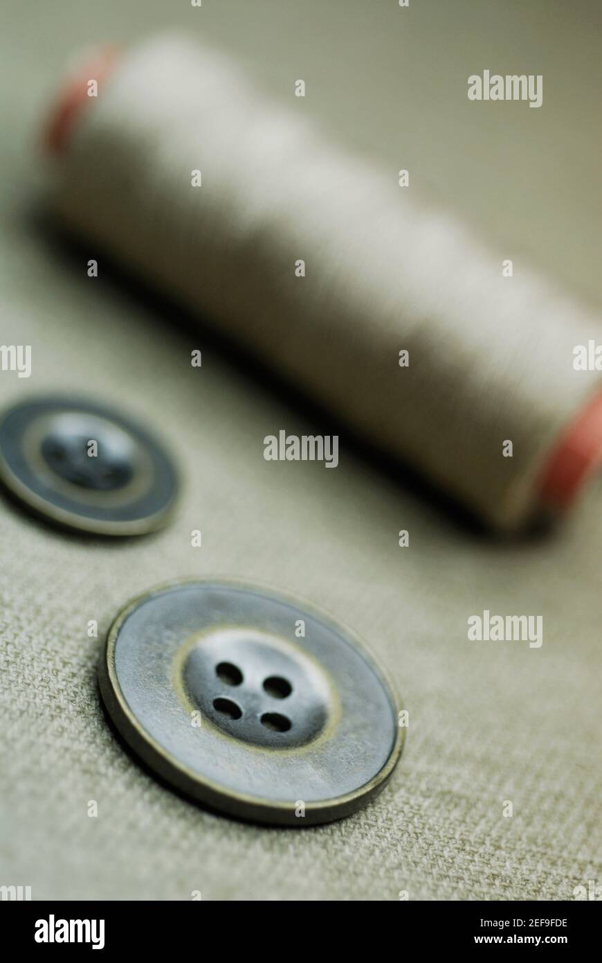Close-up of two buttons with a spool of thread Stock Photo - Alamy