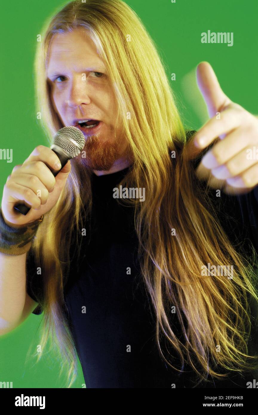 Close-up of a mid adult man singing into a microphone Stock Photo - Alamy
