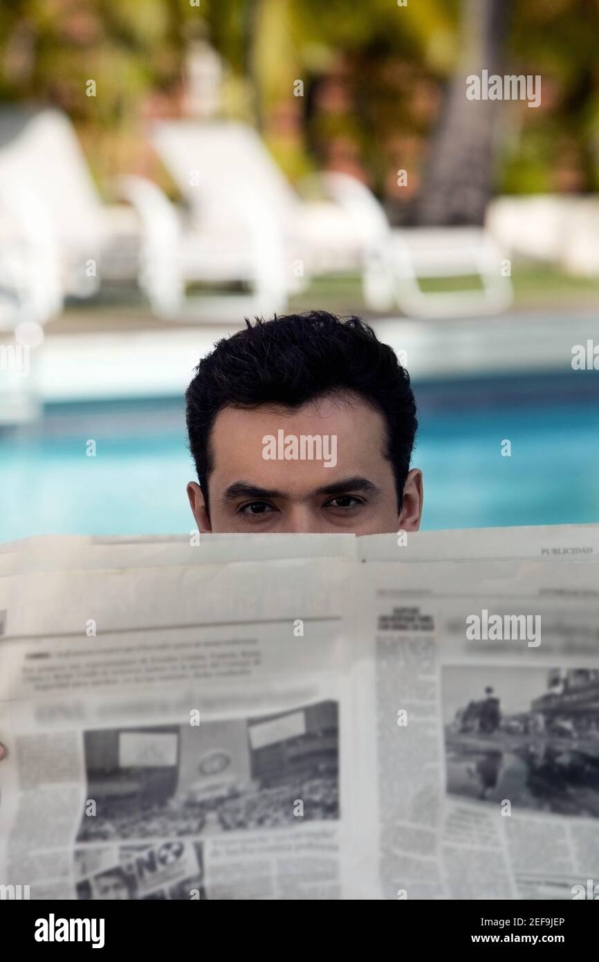 Portrait of a young man peeping over a newspaper Stock Photo - Alamy