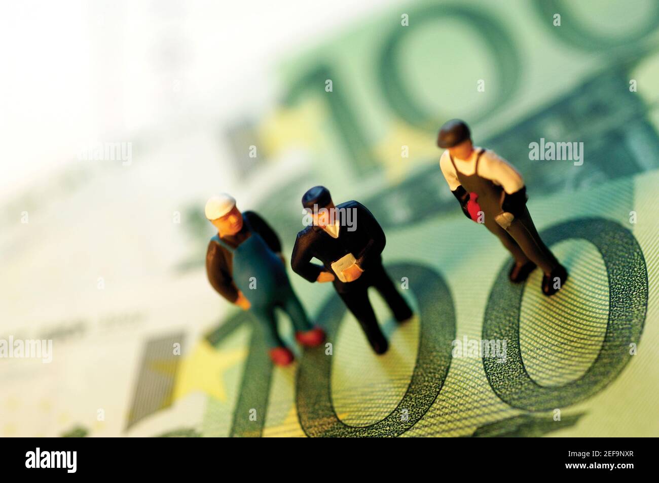 Three toy men standing on top of paper currency, close-up Stock Photo ...